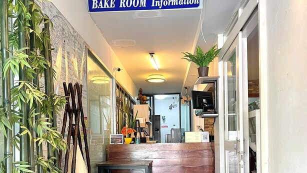 Um café com balcão de madeira, decoração em bambu e um letreiro indicando a área de preparo de pães.