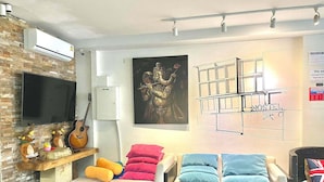 Um quarto aconchegante com lareira, televisão na parede, um violão e um quadro.