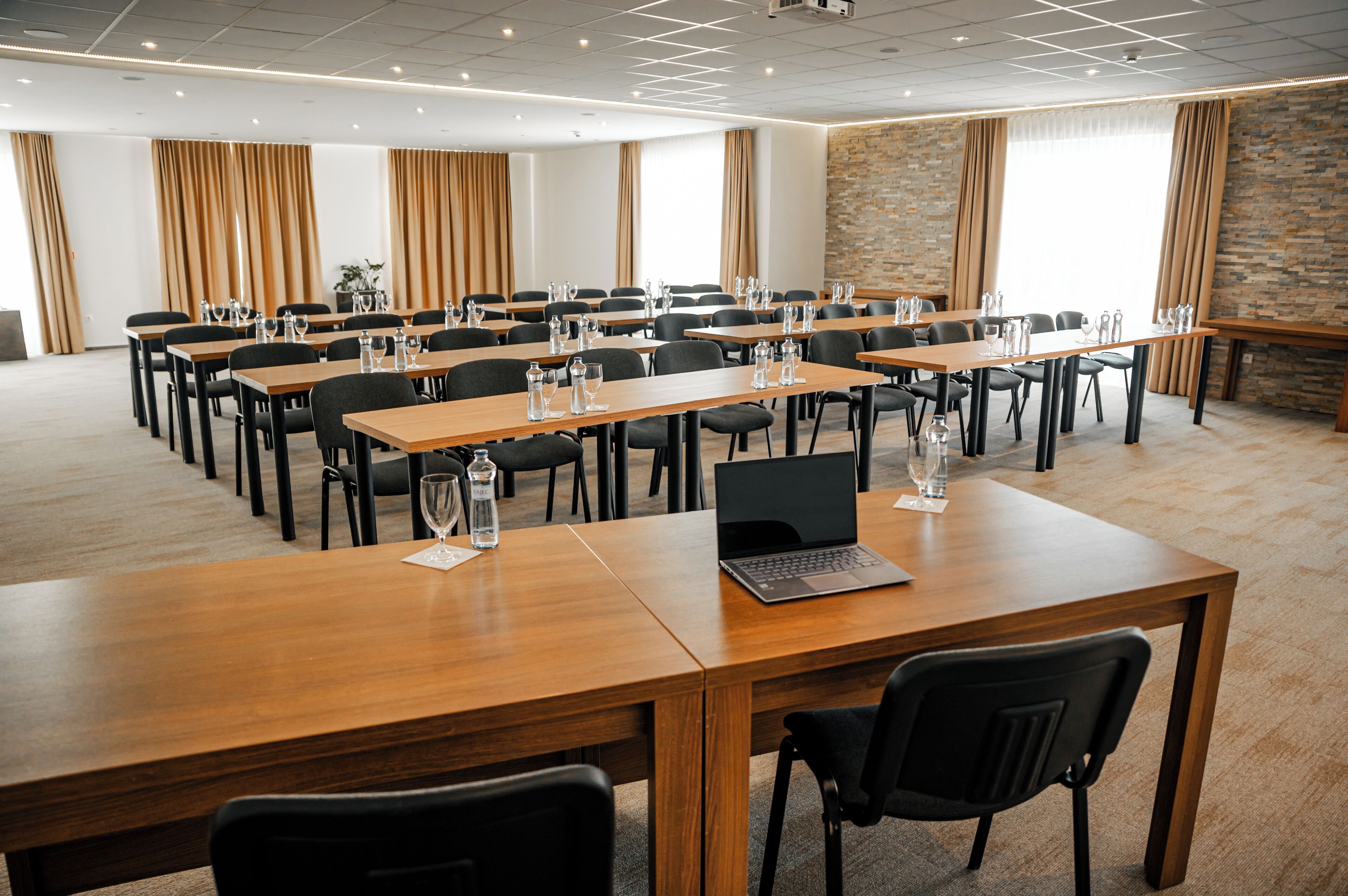 Uma sala de conferências com várias mesas, cadeiras e laptops.