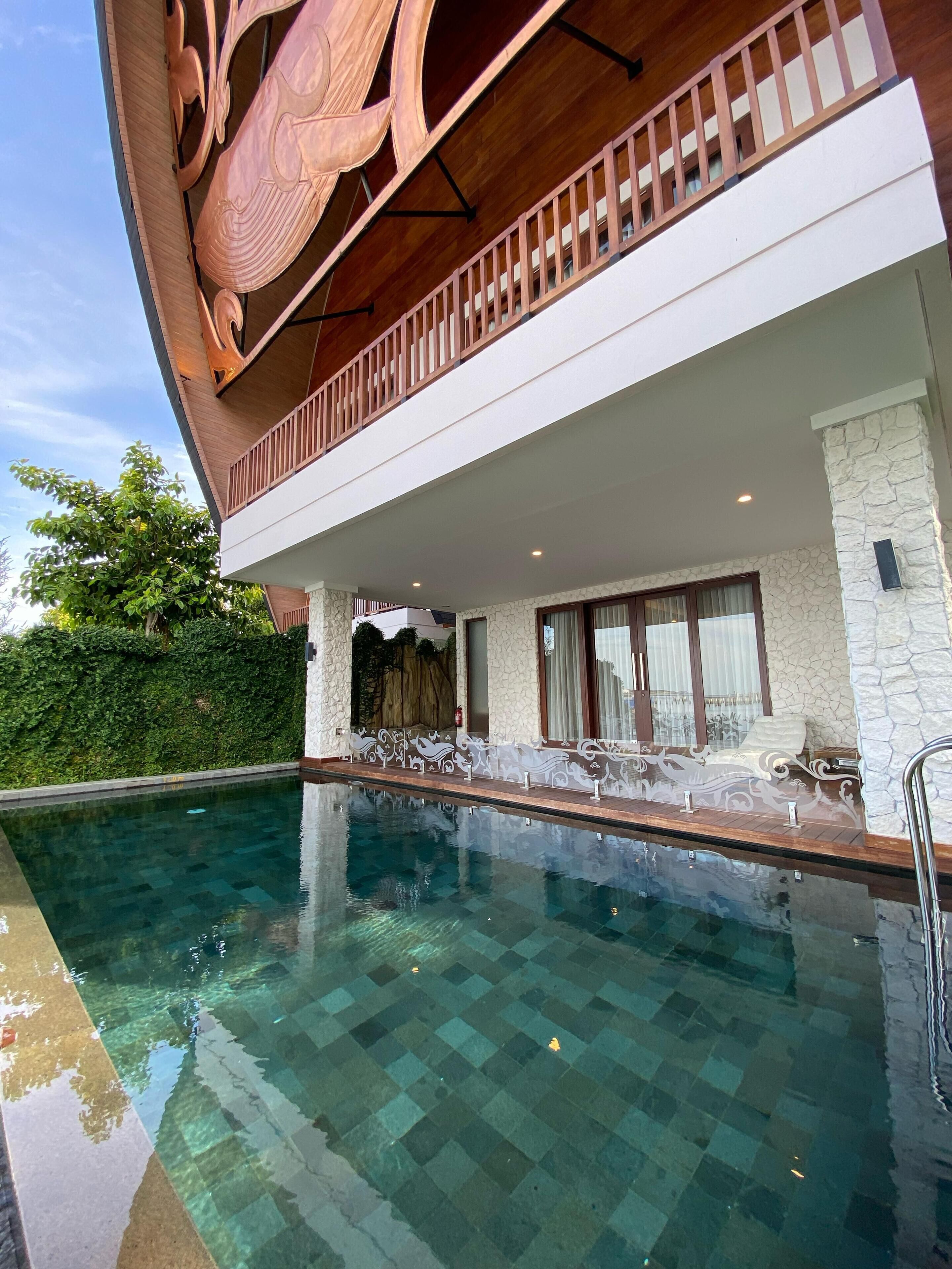 Uma área moderna à beira da piscina, com piscina cristalina, deck de madeira e varanda com guarda-corpo.