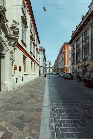 Rua com edifícios históricos, calçada pavimentada e carros estacionados.
