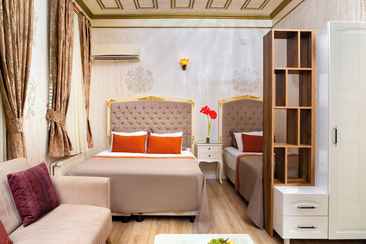 Quarto de hotel com uma cama grande, duas mesas de cabeceira, um guarda-roupa e um sofá.