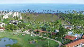 Resort com piscina, palmeiras e vista para o mar.