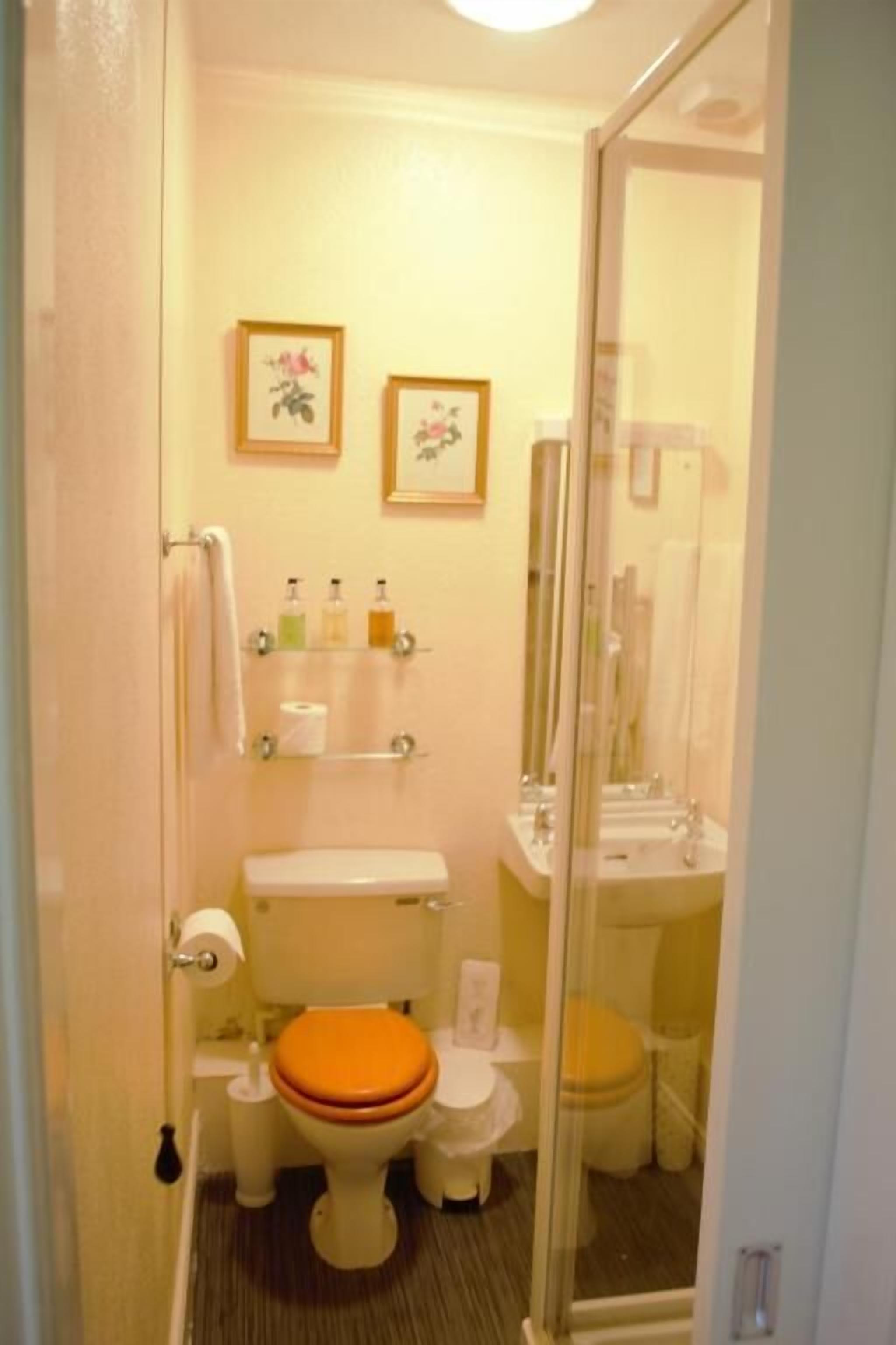 Casa de banho com duas sanitas, uma pia e zona de duche.