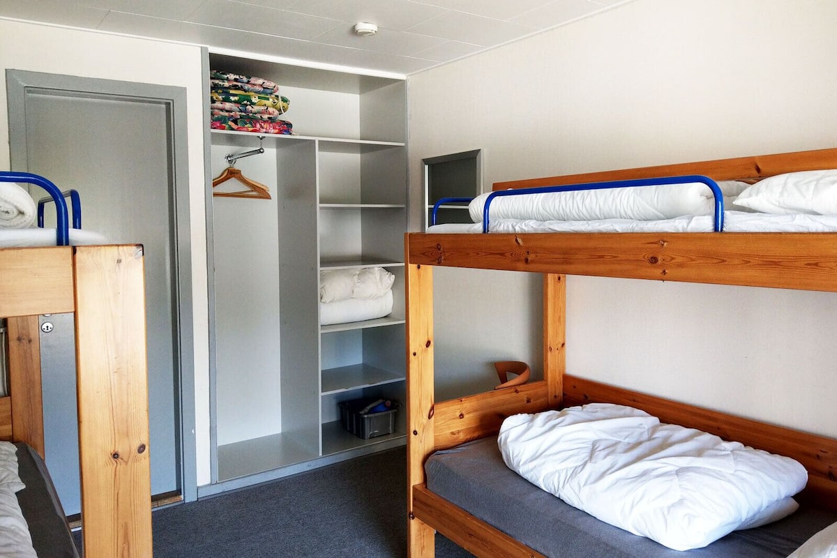 Quarto com beliche, guarda-roupa e uma mesinha.
