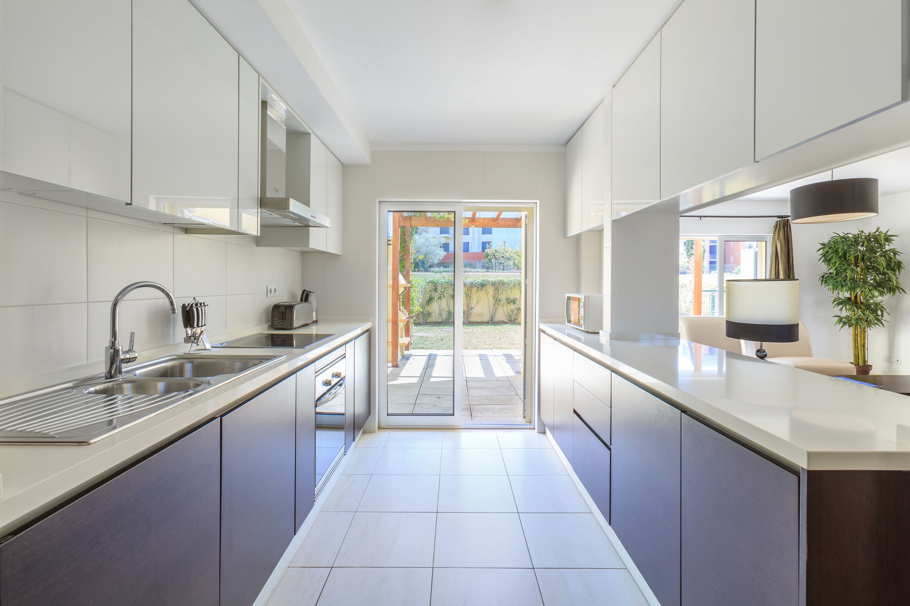 Cozinha moderna com ilha central, eletrodomésticos de aço inoxidável e vista para um pátio externo.