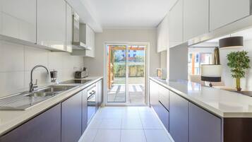 Cozinha moderna com ilha central, eletrodomésticos de aço inoxidável e vista para um pátio externo.