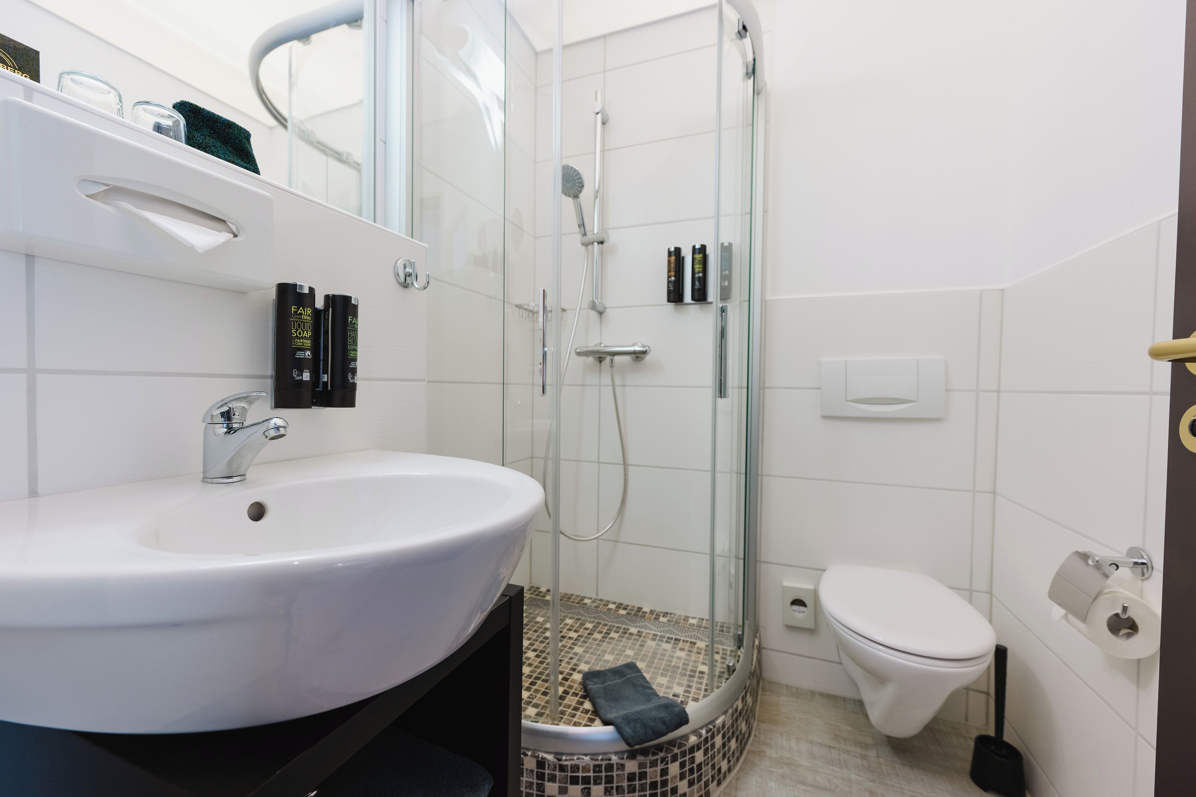 Um banheiro moderno com pia branca, chuveiro com box de vidro e vaso sanitário.