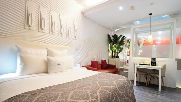Quarto moderno com uma cama grande, uma escrivaninha e uma planta.