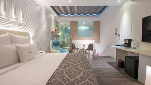 Quarto de hotel moderno com uma cama grande, uma mesa e um espaço de estar.