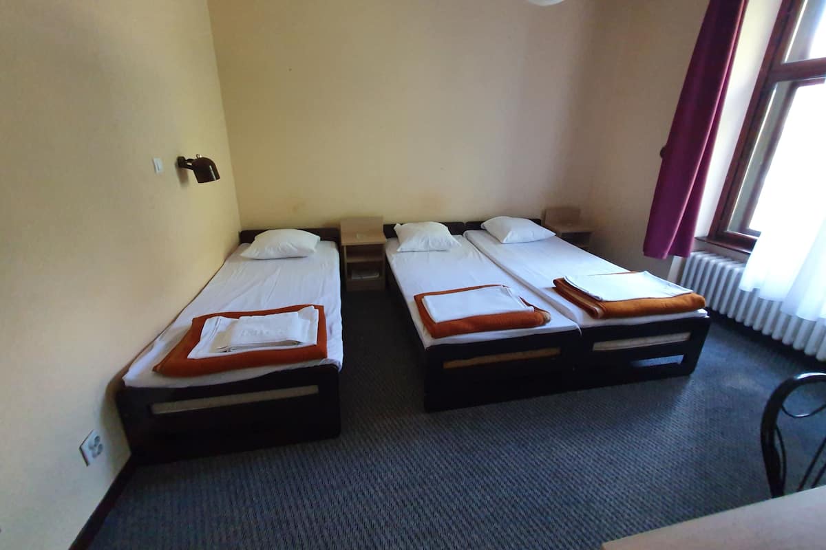 Quarto com duas camas de solteiro, uma mesa pequena e uma cadeira.