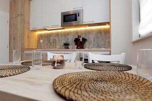Uma cozinha moderna com armários brancos, micro-ondas embutido e bancada de madeira.