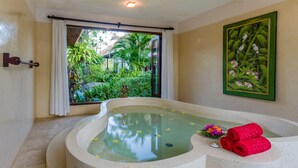 Um quarto de spa com uma banheira grande, uma janela com cortinas e um quadro emoldurado com pássaros.