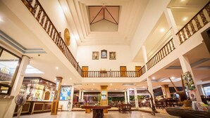 Um hall amplo com teto alto, escadaria central e área de estar.