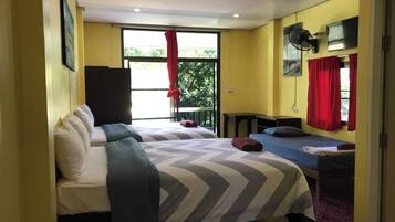 Quarto com duas camas, uma televisão e uma janela com cortinas vermelhas.