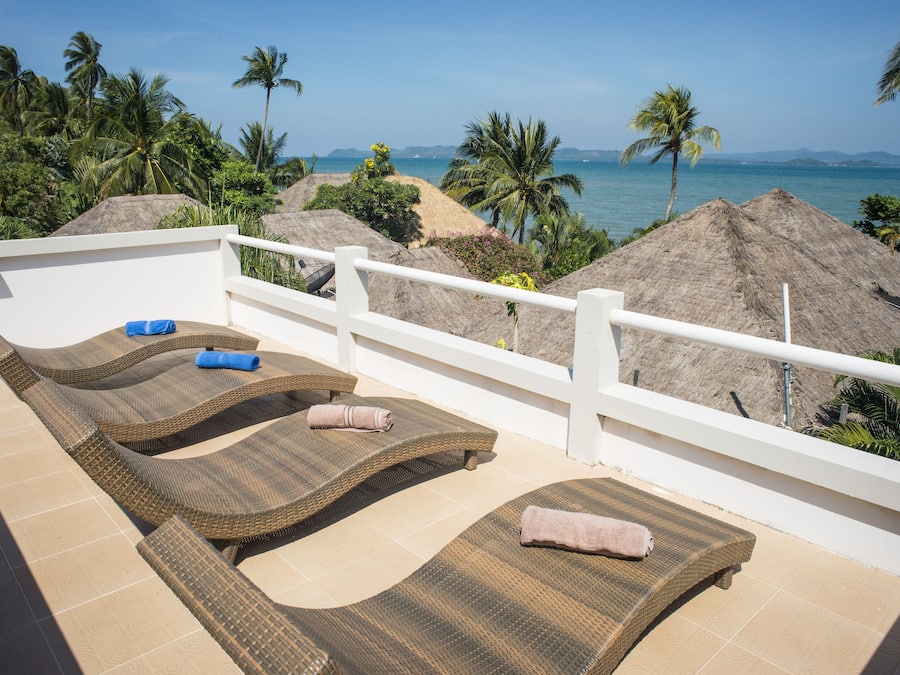 Terraço com cadeiras de descanso e vista para o mar.