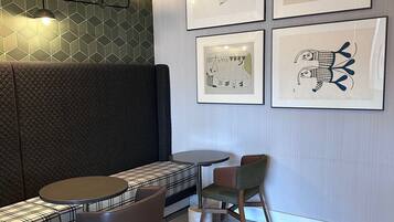 Um interior moderno com sofá, cadeiras, uma mesa pequena e obras de arte na parede.
