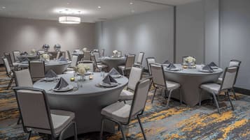 Uma sala de conferência com várias mesas redondas, cada uma disposta com cadeiras, centros de mesa e louças.