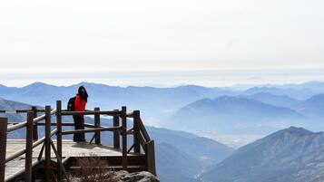 Um deck de madeira com uma pessoa em cima, com vista para uma paisagem montanhosa.