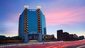 Um hotel moderno com design imponente, com entrada destacada e várias varandas.