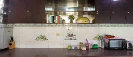 Cozinha com armários de madeira escura, painel de azulejos e diversos eletrodomésticos, incluindo uma torradeira e uma chaleira.