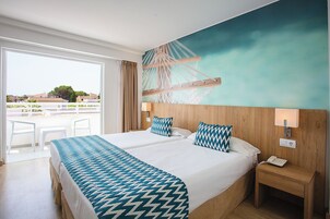 Quarto de hotel com duas camas, uma janela grande com vista e uma rede na parede.