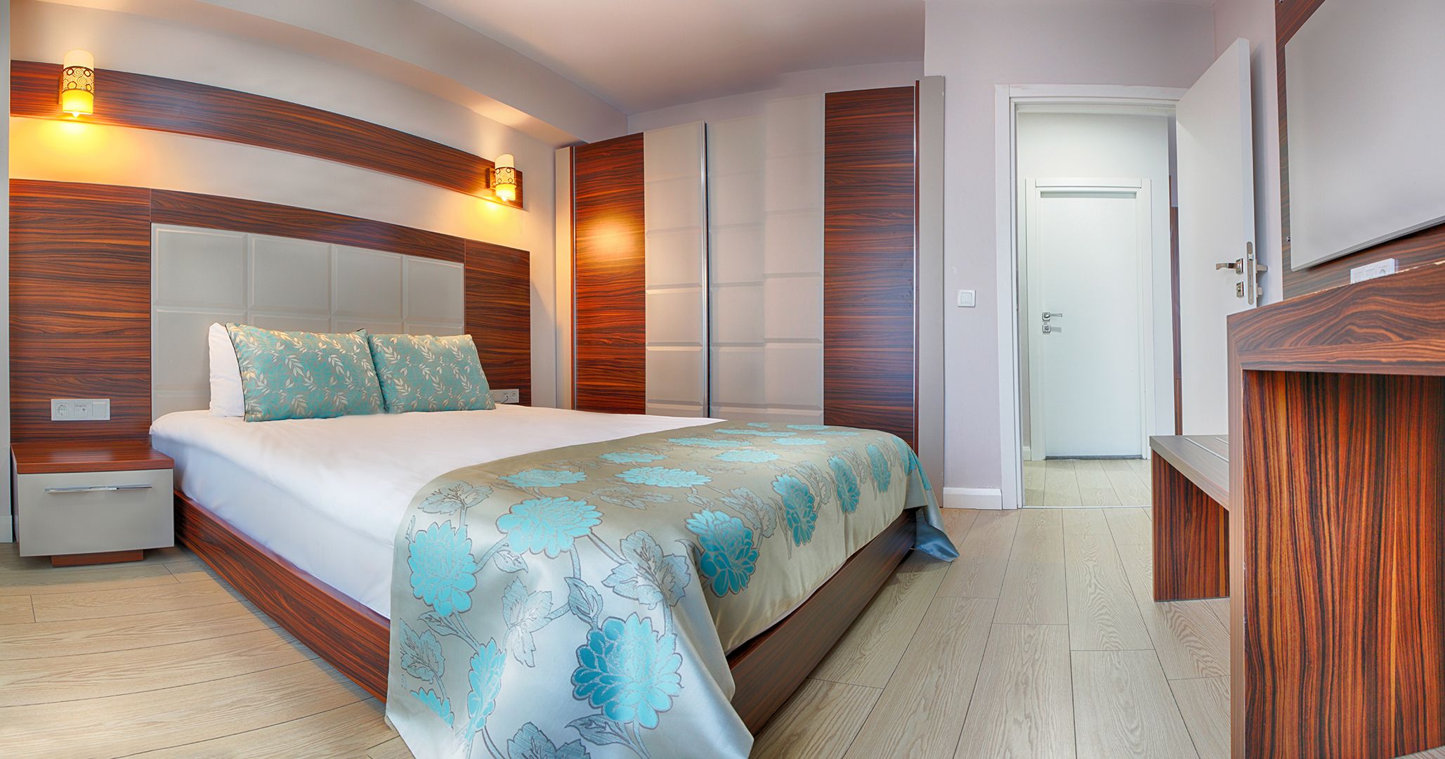 Quarto moderno com cama grande, painéis de madeira e mesa de cabeceira.