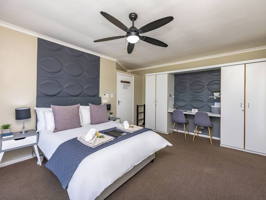Quarto de hotel moderno com uma cama grande, uma escrivaninha e um guarda-roupa.