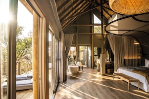 Um quarto espaçoso com uma cama grande, um espaço de estar e vista para o exterior.