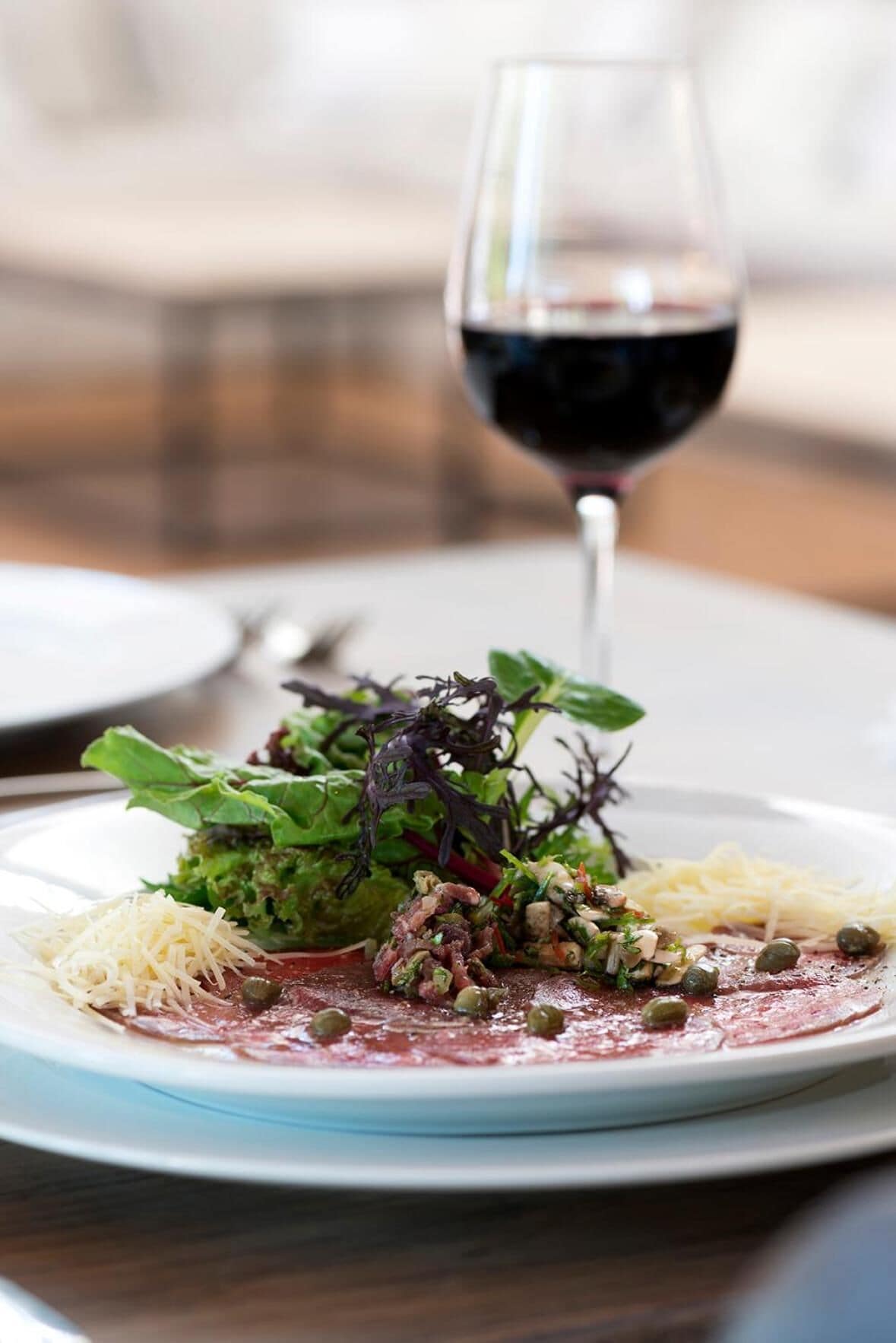 Prato de comida com um copo de vinho tinto sobre uma mesa.