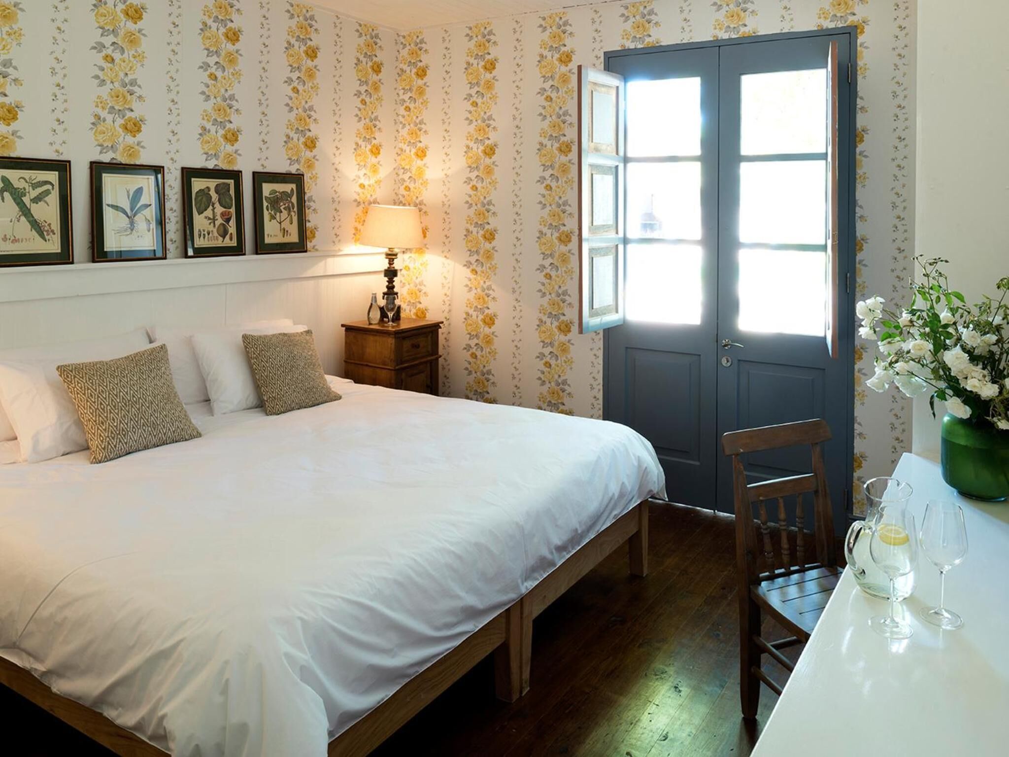 Quarto com cama, mesa de cabeceira, luminária e janela com vista.