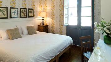 Quarto com cama, mesa de cabeceira, luminária e janela com vista.