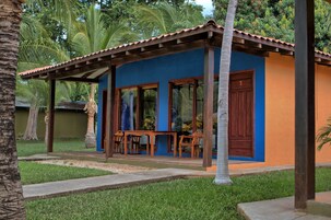 Um edifício pequeno, de um andar, com fachada azul e laranja, móveis de madeira e telhado de azulejos.