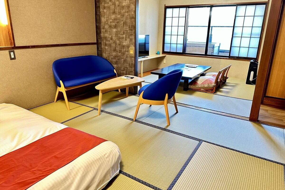 Quarto com tatame, uma cama, uma escrivaninha e duas cadeiras azuis.