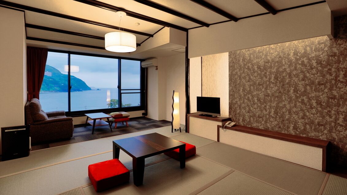 Quarto de hotel moderno com uma janela grande, um sofá, uma mesa e uma televisão.