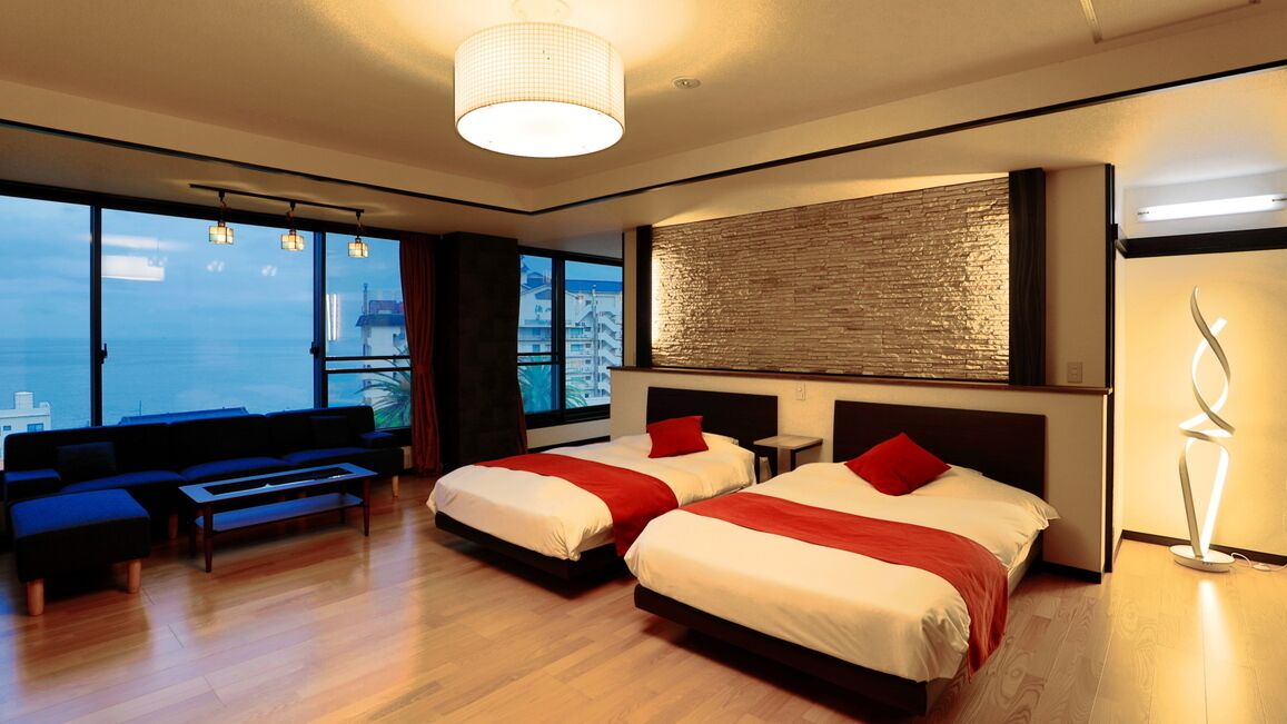 Quarto de hotel moderno com duas camas, um sofá, uma janela ampla com vista e uma peça de arte original na parede.