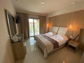 Quarto de hotel com uma cama grande, mesa de cabeceira, espelho e vista para o exterior.