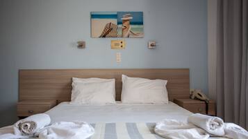 Cama bem arrumada com lençóis brancos e roupa de cama listrada, cabeceira de madeira e um quadro sobre a cama.