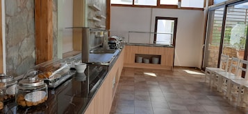 Cozinha moderna com bancada de vidro, eletrodomésticos de aço inoxidável e parede de pedra.