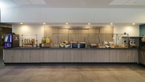 Uma barra de pequeno-almoço moderna com uma máquina de café, cestos de fruta e copos.