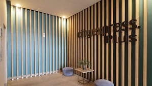 Um lobby moderno com ripas verticais de madeira, um balcão de recepção, duas áreas de estar acolchoadas e uma placa com a inscrição "cityexpress plus".