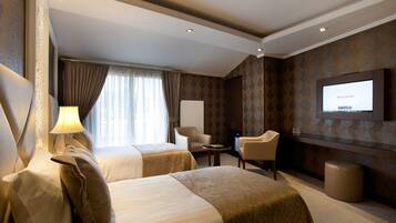 Quarto de hotel com duas camas, uma televisão, uma escrivaninha e uma cadeira.