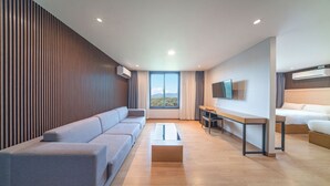Uma sala de estar moderna com sofá, mesa de centro, televisão e vista para o exterior.