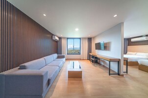 Uma sala de estar moderna com sofá, mesa de centro, televisão e vista para o exterior.