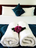 Cama bem arrumada com lençóis brancos e almofada verde-água.