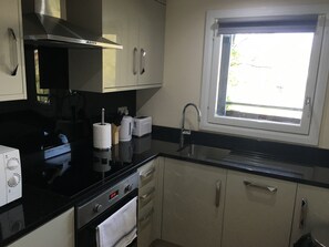 Um frigorífico, um micro-ondas, um forno, uma cafeteira/bule
