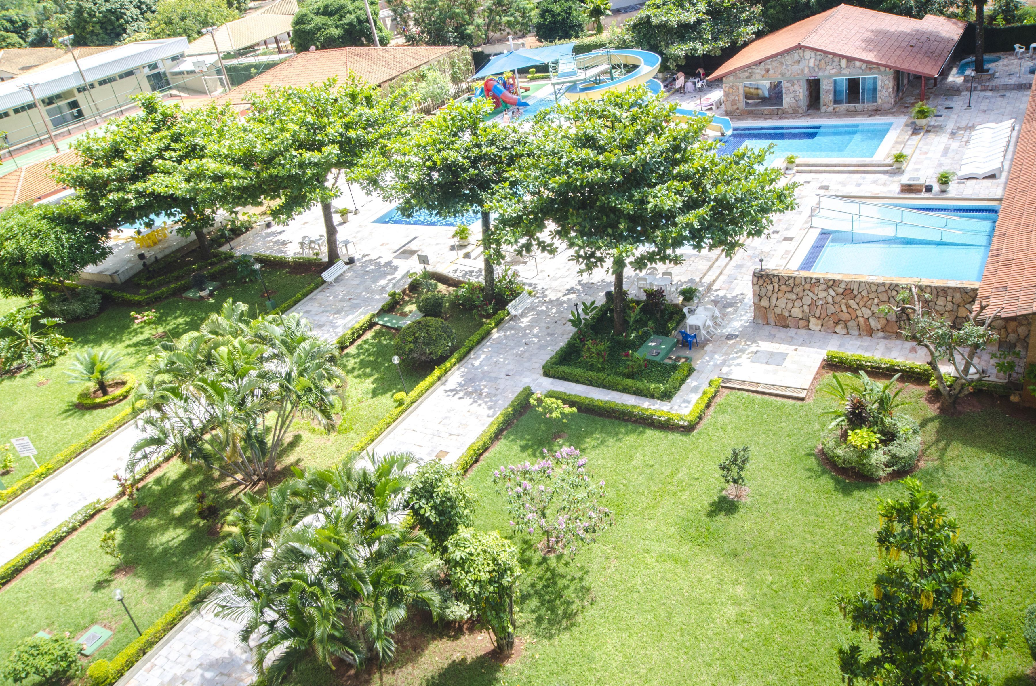 Uma área ajardinada com piscina, edifícios de pedra e vegetação bem cuidada.