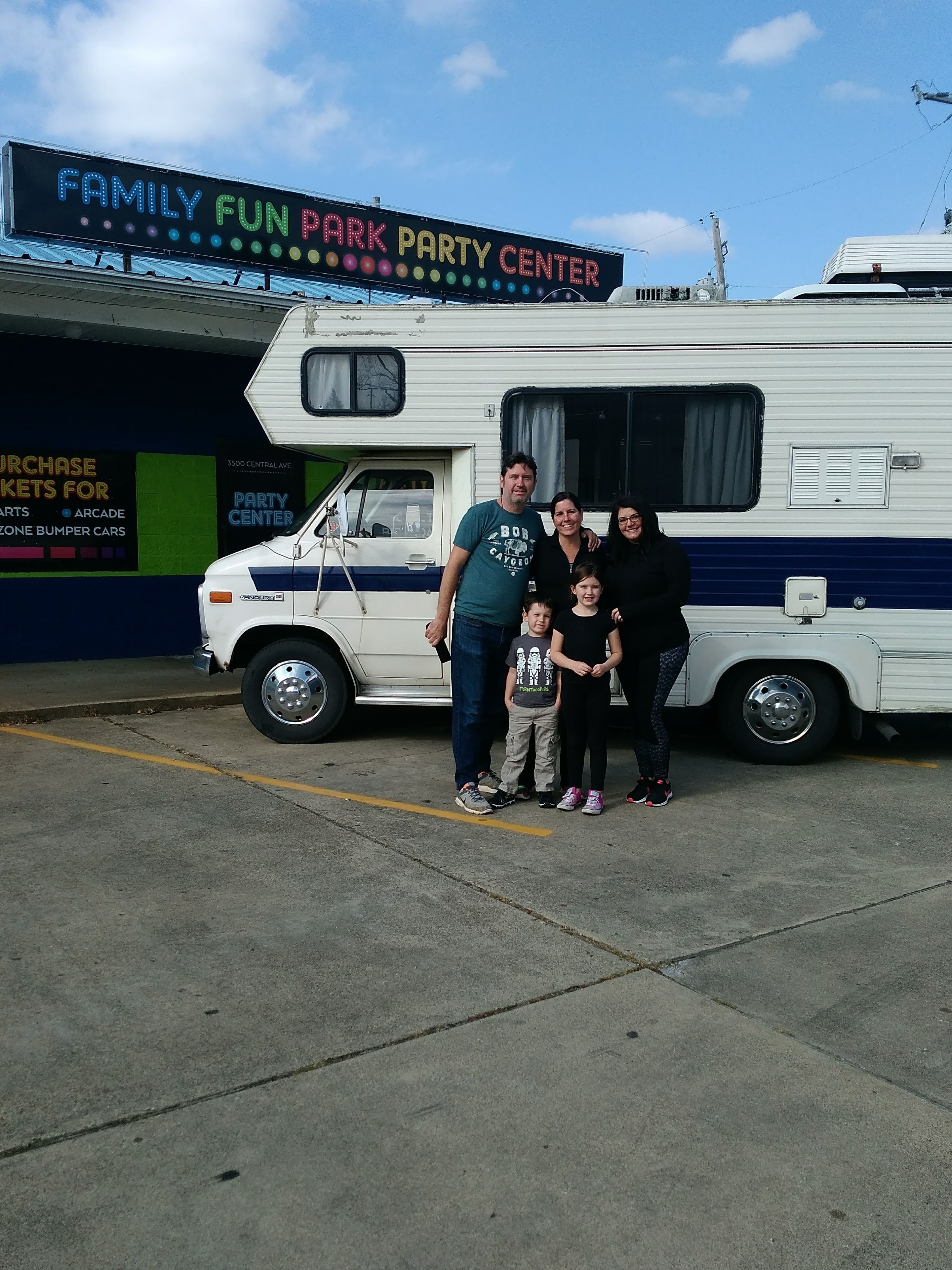 Uma família posando em frente a uma motorhome branca estacionada no Family Fun Park Party Center.