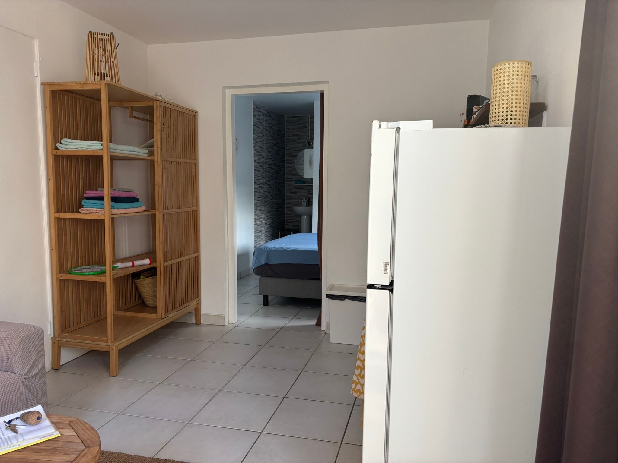 Quarto compacto com cama, armário e geladeira.