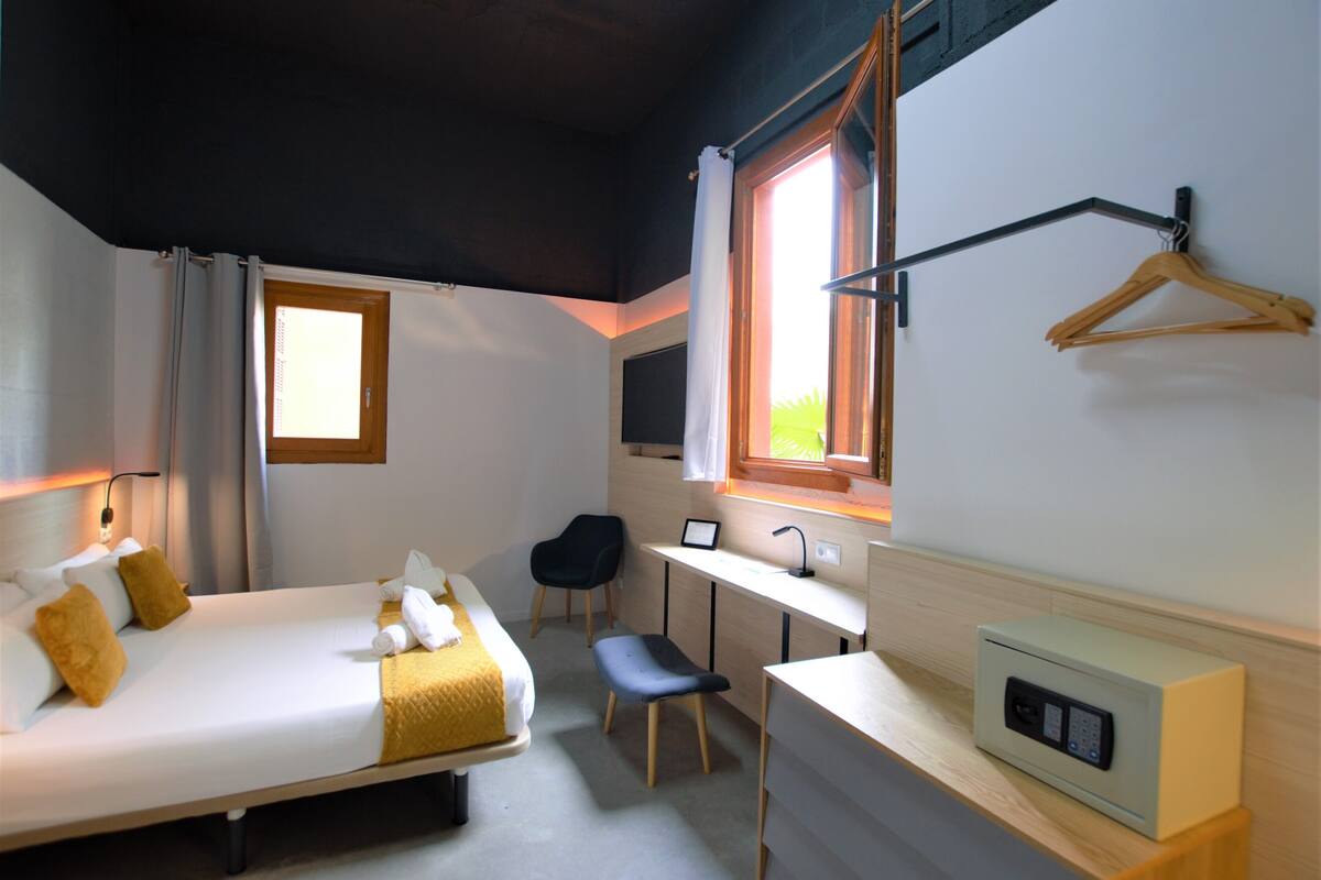 Quarto com cama, escrivaninha, cadeira e micro-ondas.